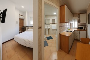 Quarto compacto com cama, banheiro pequeno e cozinha compacta.