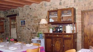 Uma área de jantar rústica com paredes de pedra, móveis de madeira e um aparador com copos.