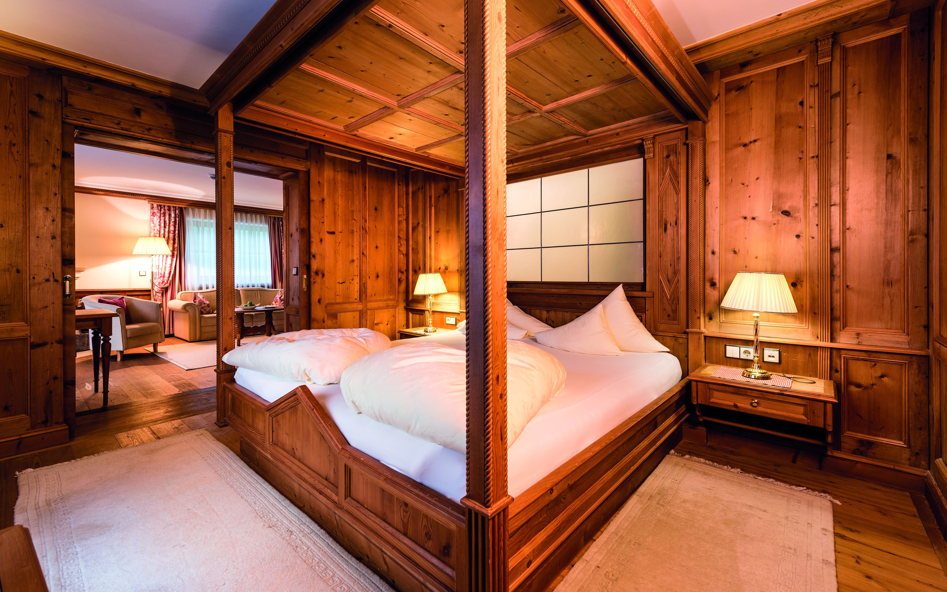 Uma cama de dossel com lençóis brancos, paredes de madeira e teto de madeira.