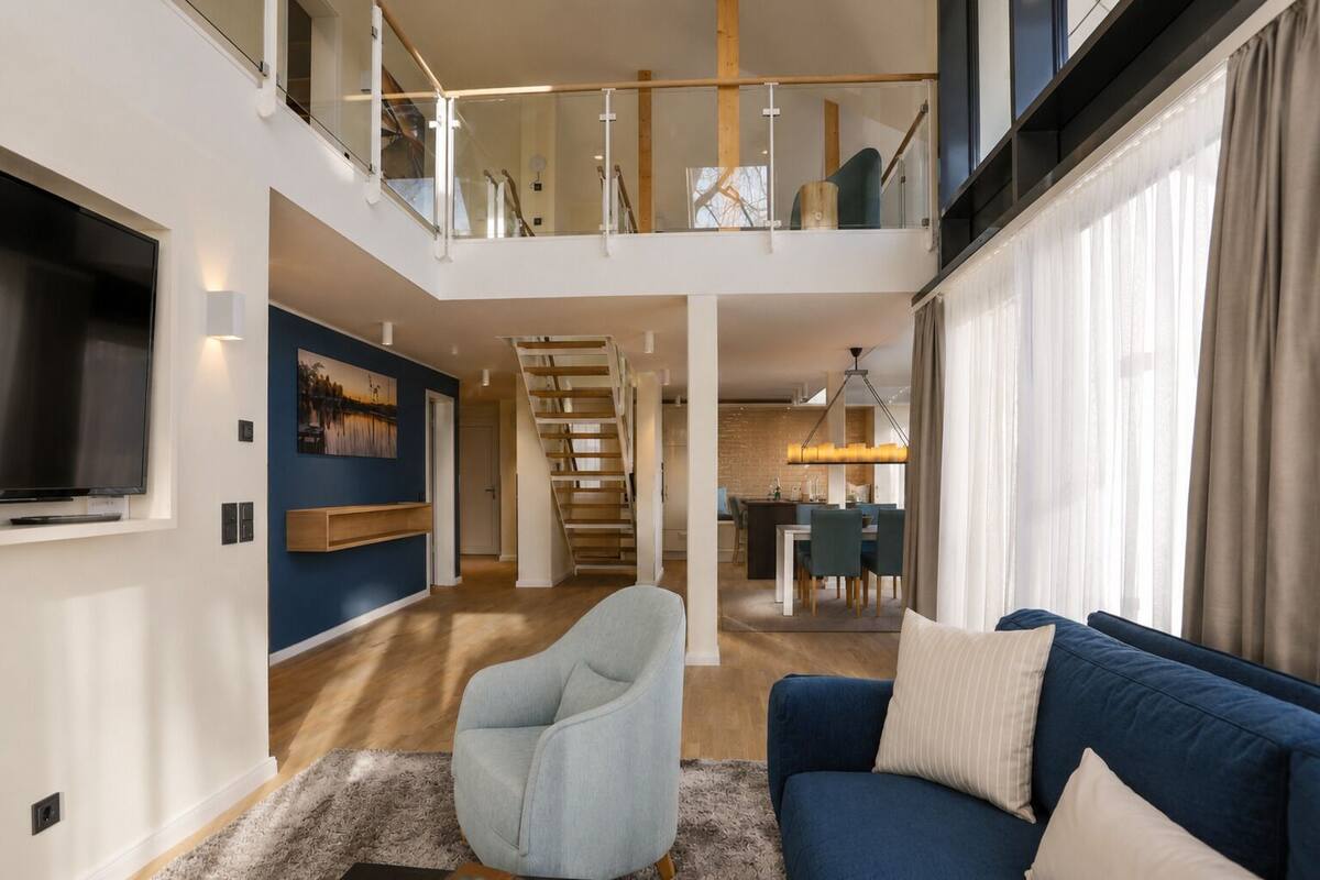 Uma sala de estar moderna com sofá, poltrona e escada para uma varanda.