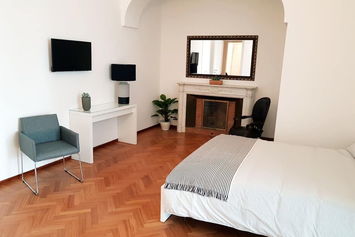 Quarto moderno com cama, escrivaninha, cadeira, lareira e espelho.
