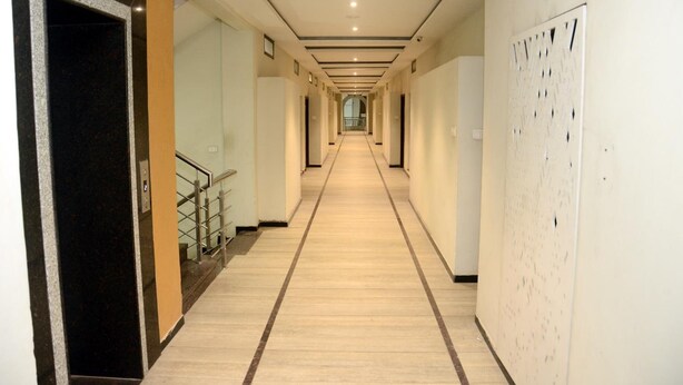 Um corredor longo e estreito com um caminho central, ladeado por paredes com um painel decorativo à direita.