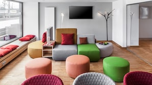 Uma sala de estar moderna com sofá, pufes, televisão de tela plana e vista para o exterior.
