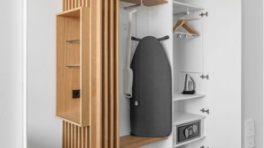 Um guarda-roupa moderno com organizador de madeira, cabideiro e tábua de passar embutida.