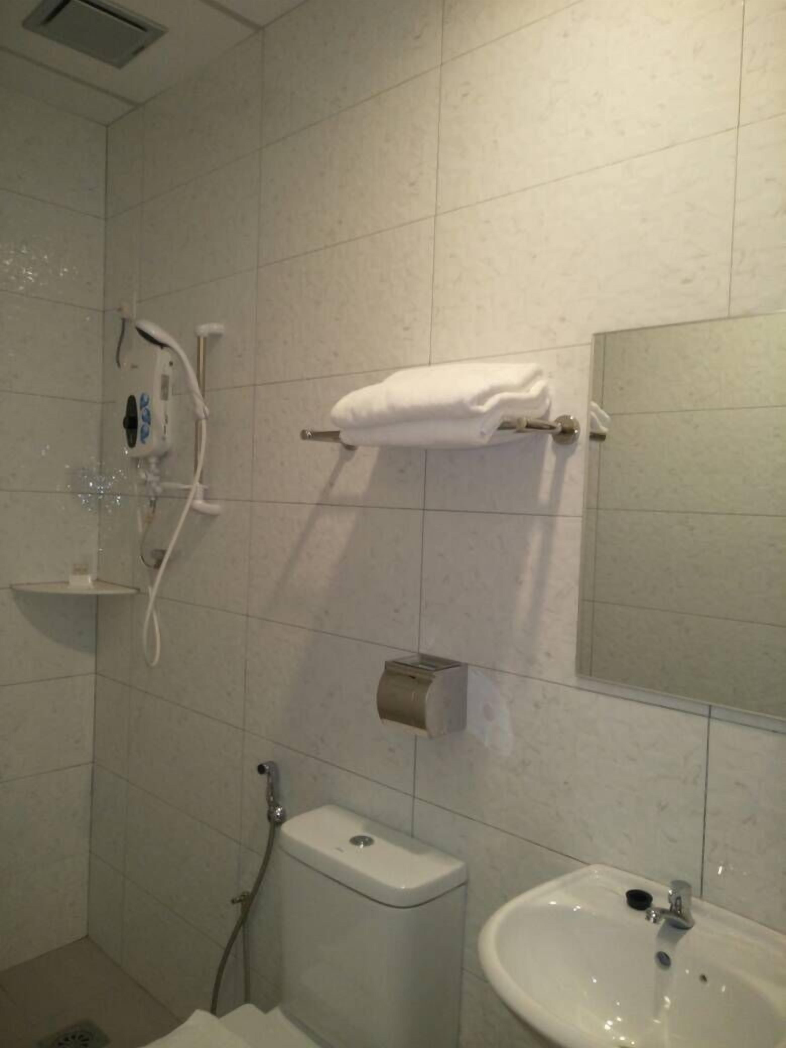 Casa de banho com sanita, lavatório e chuveiro.