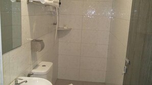 Um banheiro pequeno e limpo, com pia, vaso sanitário e chuveiro.