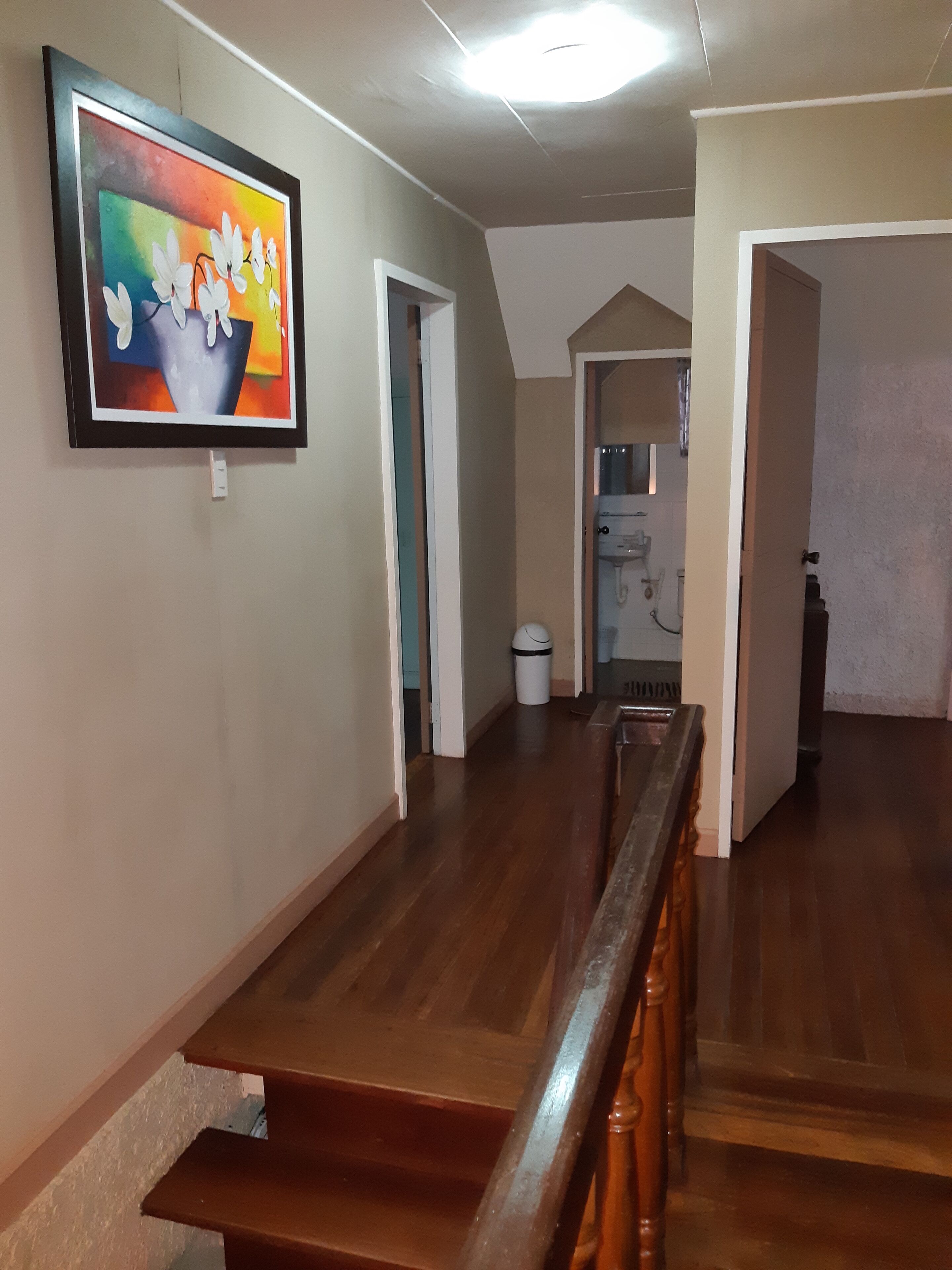 Um corredor amplo com piso de madeira e escada com corrimão de madeira.