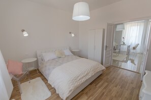 Quarto com cama, mesas de cabeceira, espelho e guarda-roupa.