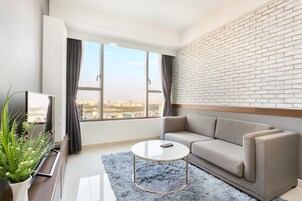 Uma sala de estar moderna com um sofá, uma mesa de centro, uma televisão e uma janela grande com cortinas.