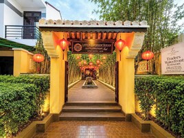 Entrada com uma placa indicando Little Riverside Hoian, um hotel boutique, e um restaurante à beira-rio.