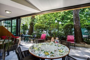 Uma área de estar moderna ao ar livre, com cadeiras de vime e uma mesa redonda com padrão floral.