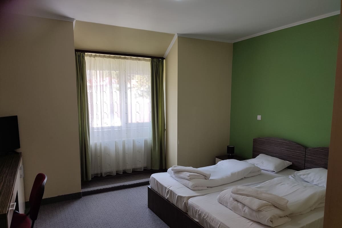 Quarto de hotel com cama, escrivaninha e cadeira.
