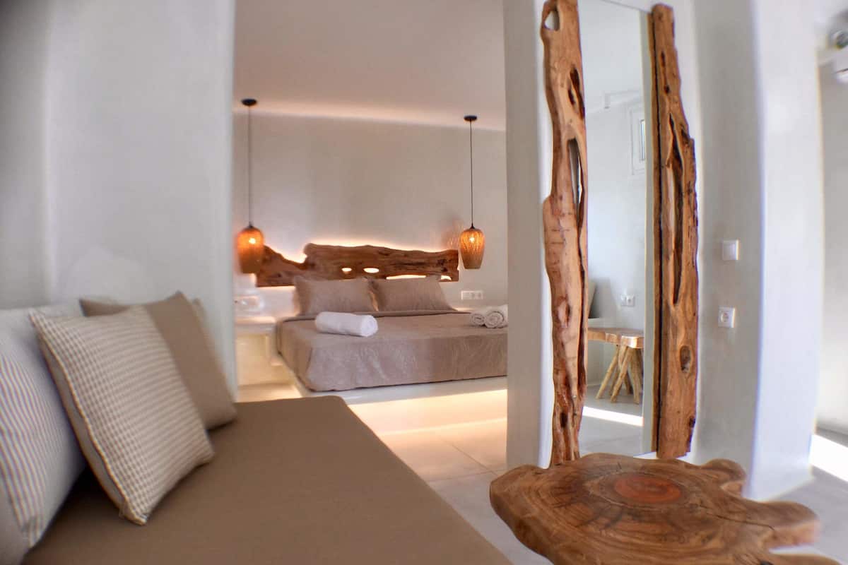 Quarto moderno com uma cama grande, mesa de cabeceira de madeira e um espelho.