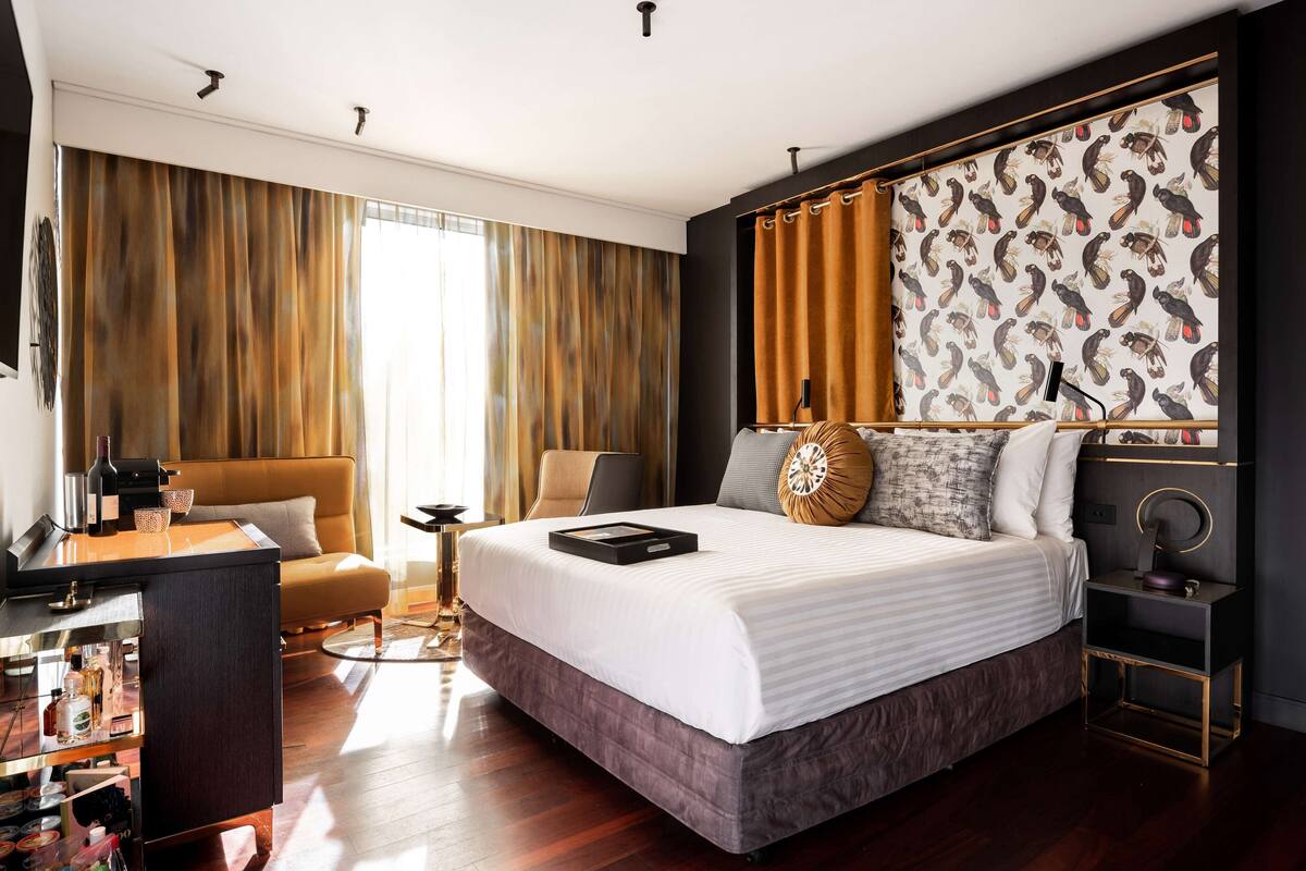Quarto de hotel moderno com uma cama grande, uma escrivaninha e uma cadeira.