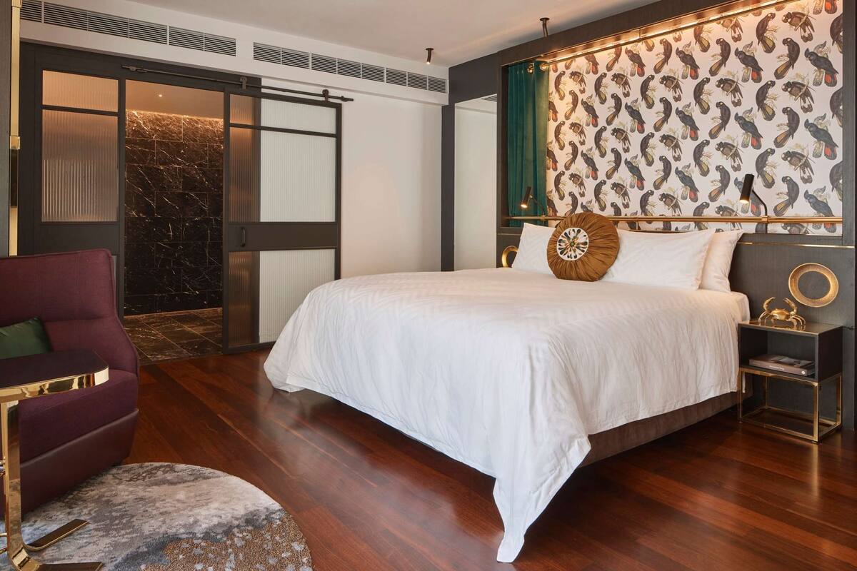 Quarto moderno com uma cama grande, uma poltrona roxa e uma parede de mármore.