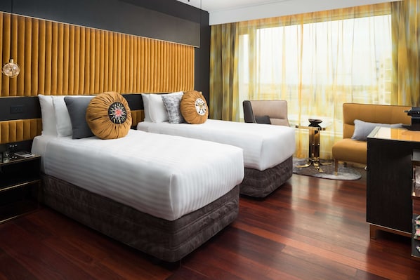 Quarto de hotel com duas camas, uma escrivaninha e uma cadeira.