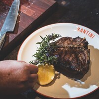 Prato com bife e alecrim, identificado como 'SANTINI'.