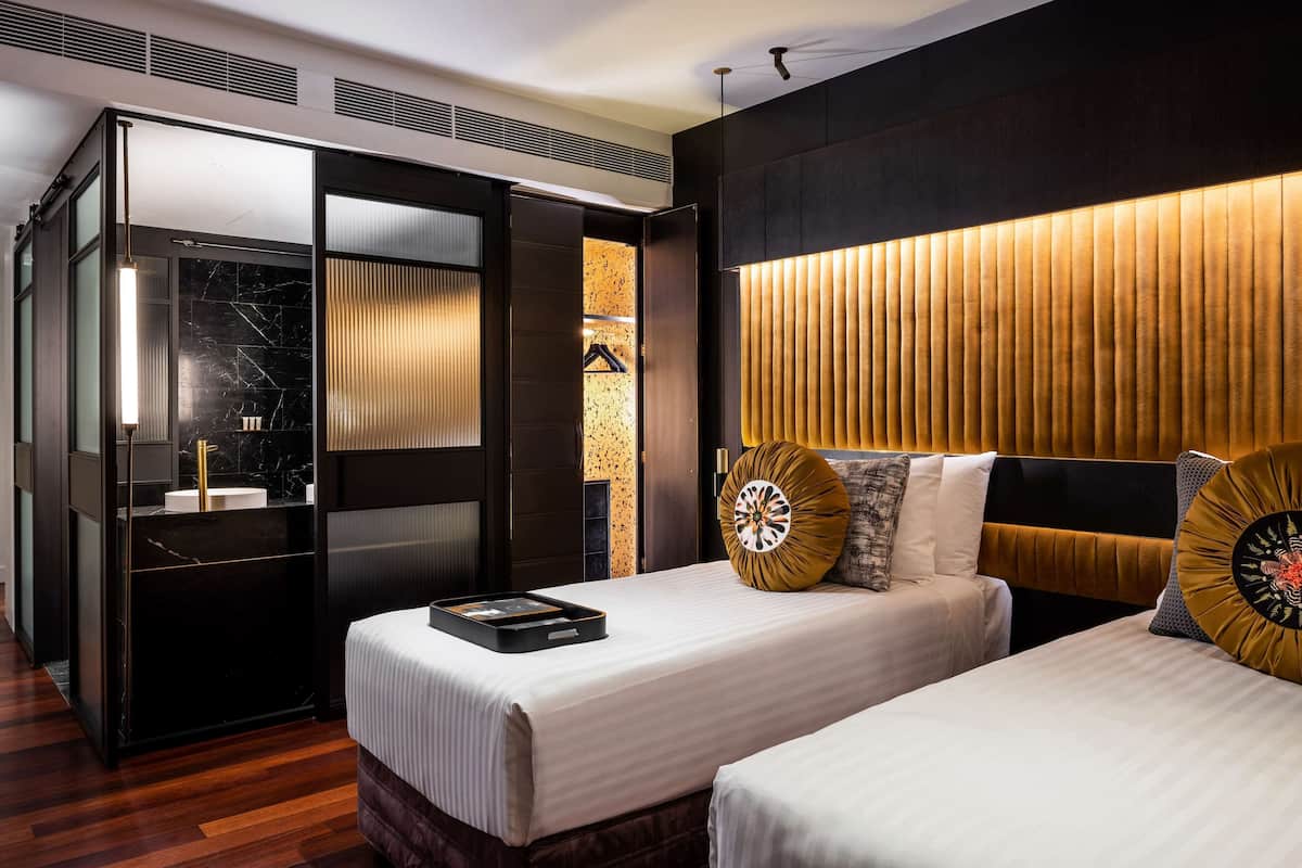 Quarto de hotel moderno com cama grande, área de estar separada e armário embutido.