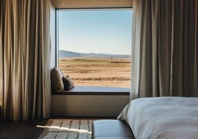 Quarto com uma grande janela, uma cama e vista para a paisagem.