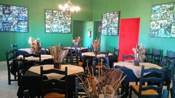Um restaurante com mesas redondas, cadeiras e obras de arte nas paredes.