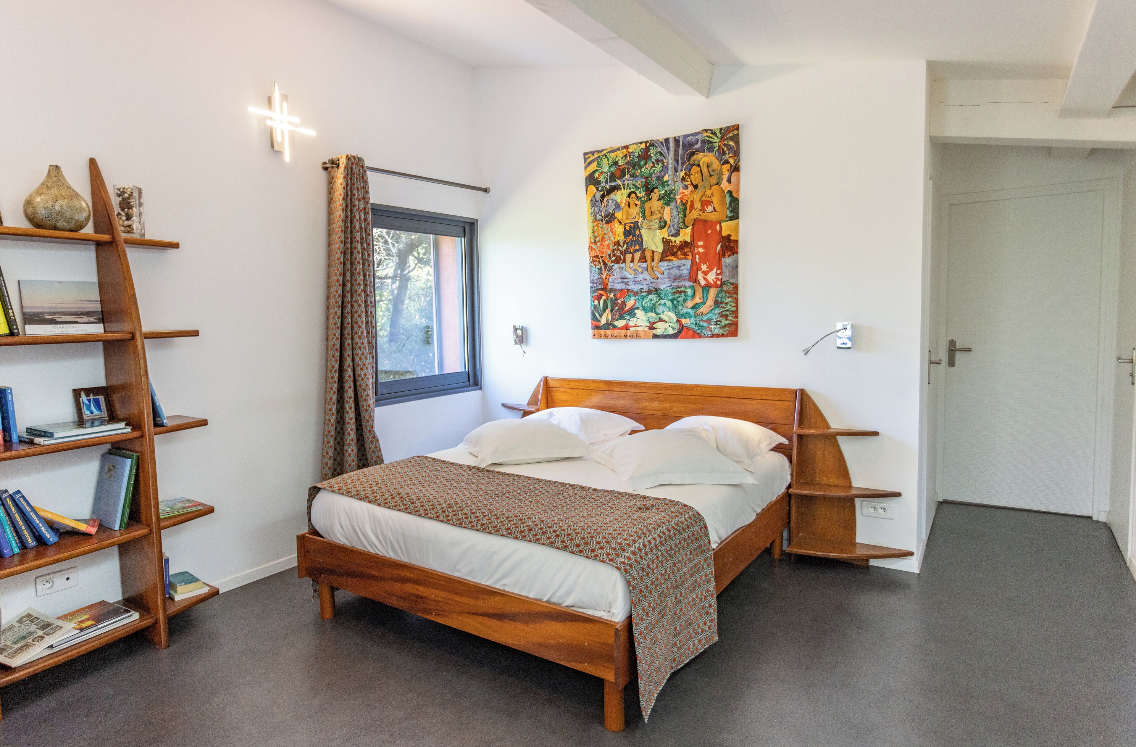 Quarto com cama de madeira, estante, janela com cortinas e um quadro na parede.