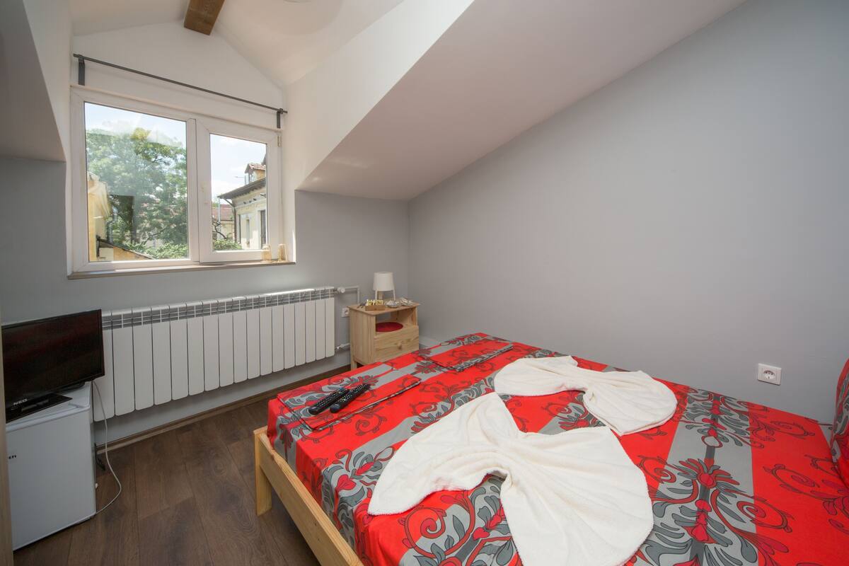 Quarto com cama, televisão, aquecedor e janela.