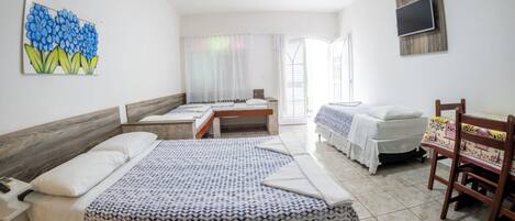 Quarto de hotel com cama, cadeira, televisão e um quadro na parede.