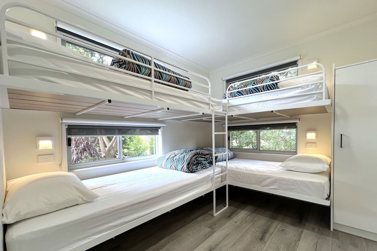 Quarto com beliche, janela e guarda-roupa.