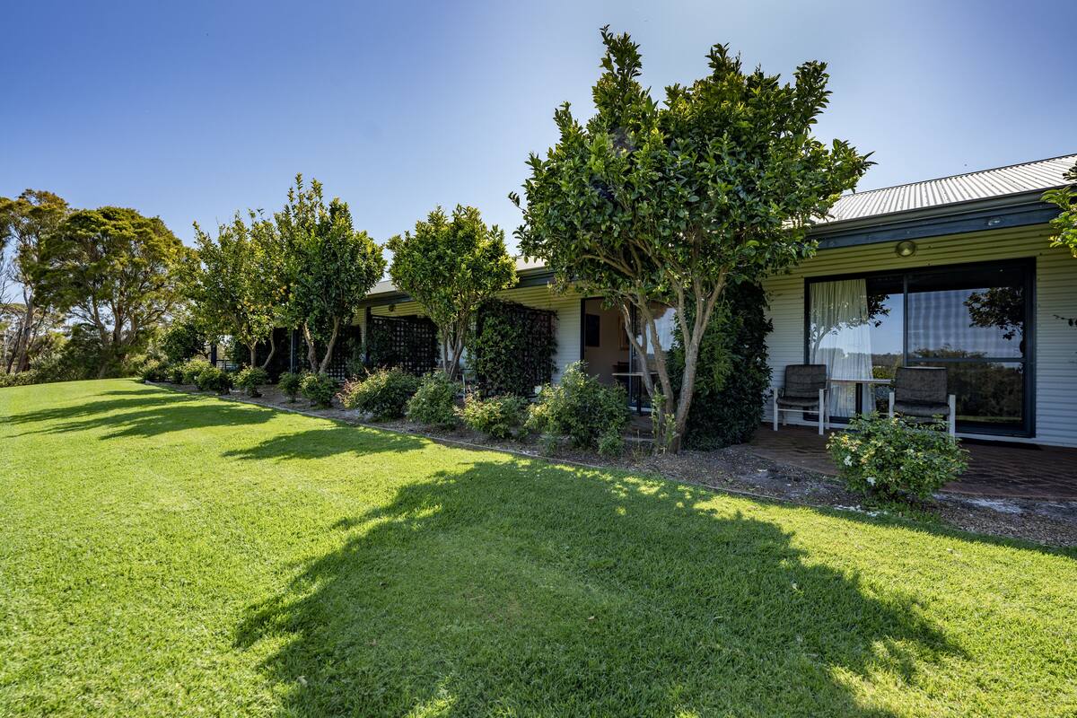 Uma casa com gramado bem cuidado, um pátio com móveis de exterior e uma grande janela.