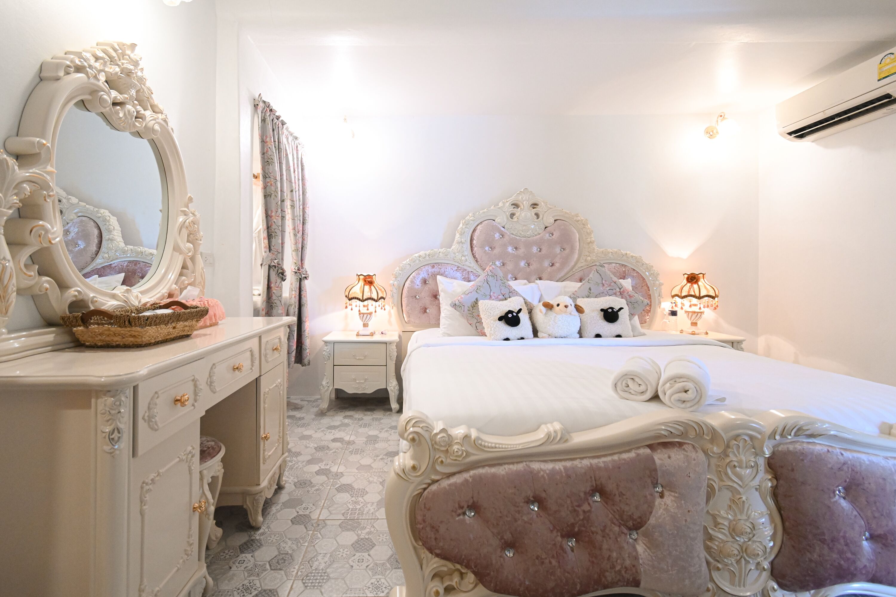 Quarto com um espelho grande e ornamentado, cabeceira estofada e almofadas decorativas.