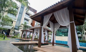Um resort com áreas de estar ao ar livre, piscina e edifícios modernos ao fundo.