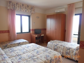 Quarto de hotel com duas camas, uma escrivaninha, televisão e guarda-roupa.
