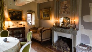 Quarto com lareira, sofá, mesa com abajur e obras de arte emolduradas nas paredes.