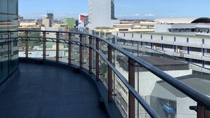 Uma varanda com vista para a paisagem urbana, incluindo um prédio alto e guindastes de construção.