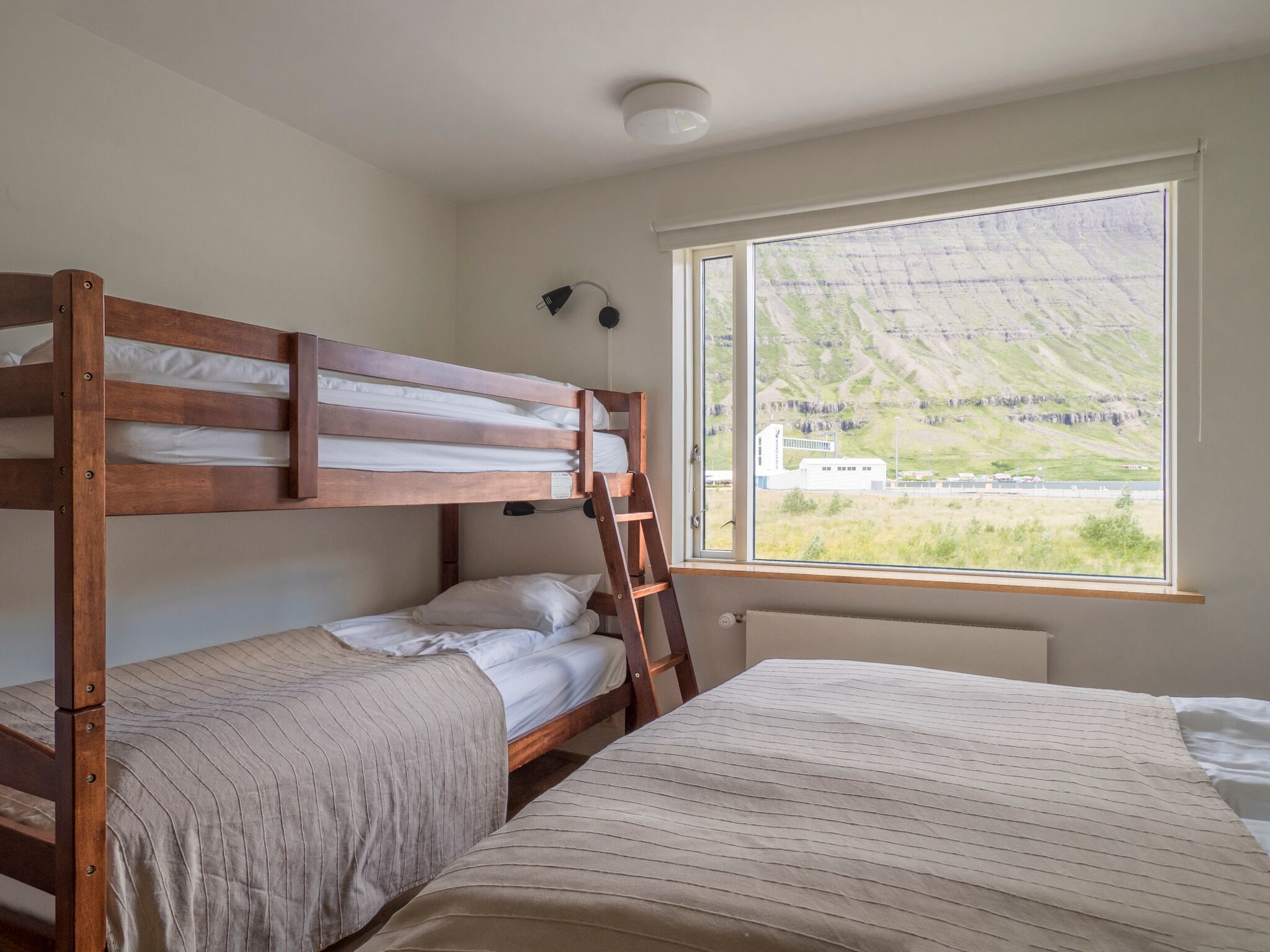 Quarto com beliches e vista para uma paisagem montanhosa através de uma grande janela.