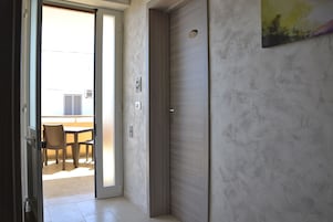 Corredor interno com porta deslizante que dá para área externa com mesa e cadeiras.