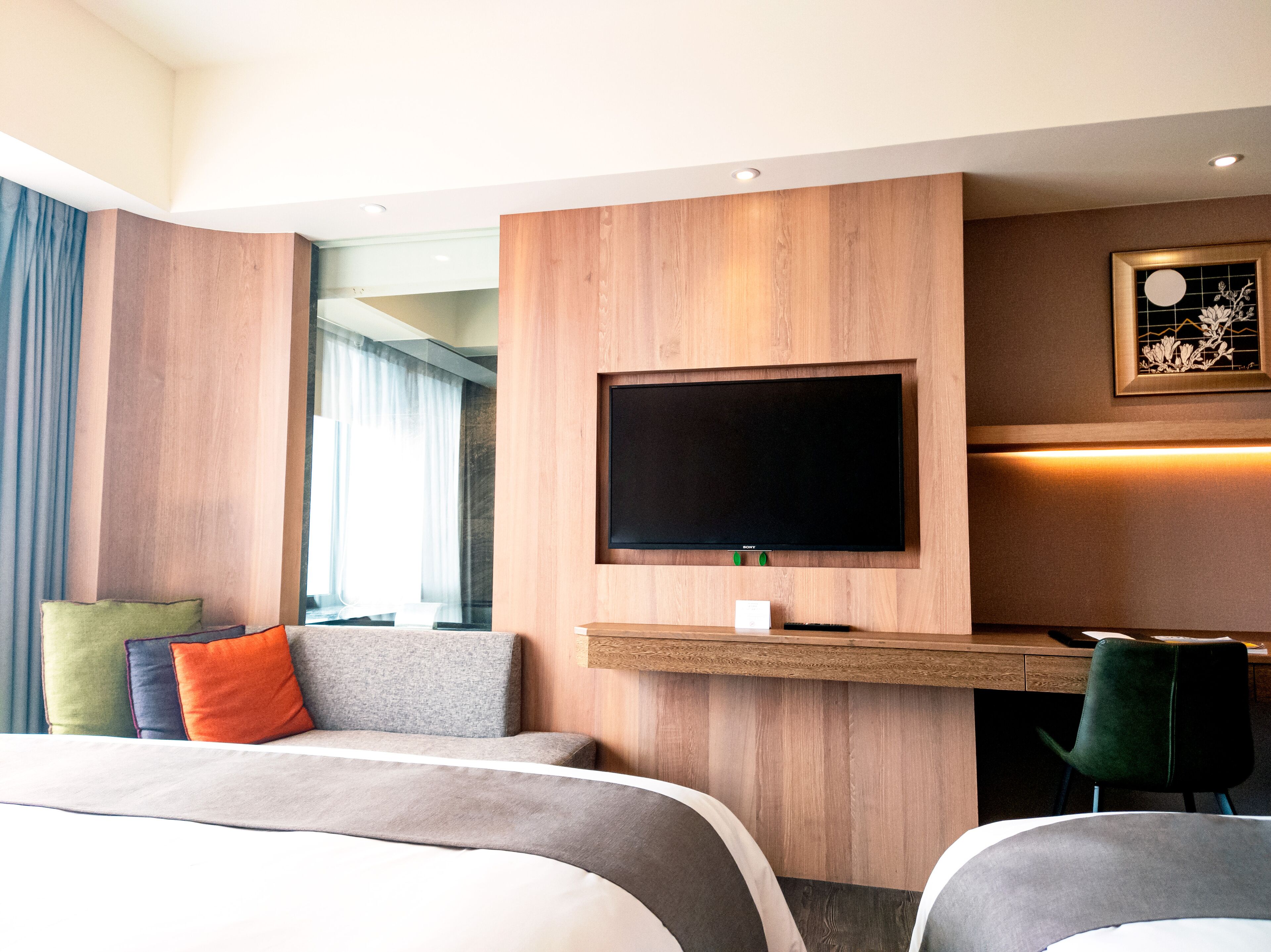 Quarto de hotel moderno com uma cama grande, uma escrivaninha e uma TV de tela plana na parede.