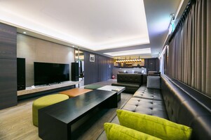 Um hall de hotel moderno com televisão de tela plana, área de estar e um bar.