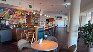 Uma área de bar moderna com balcão, banquetas e um espaço de estar com uma mesa redonda e cadeiras.