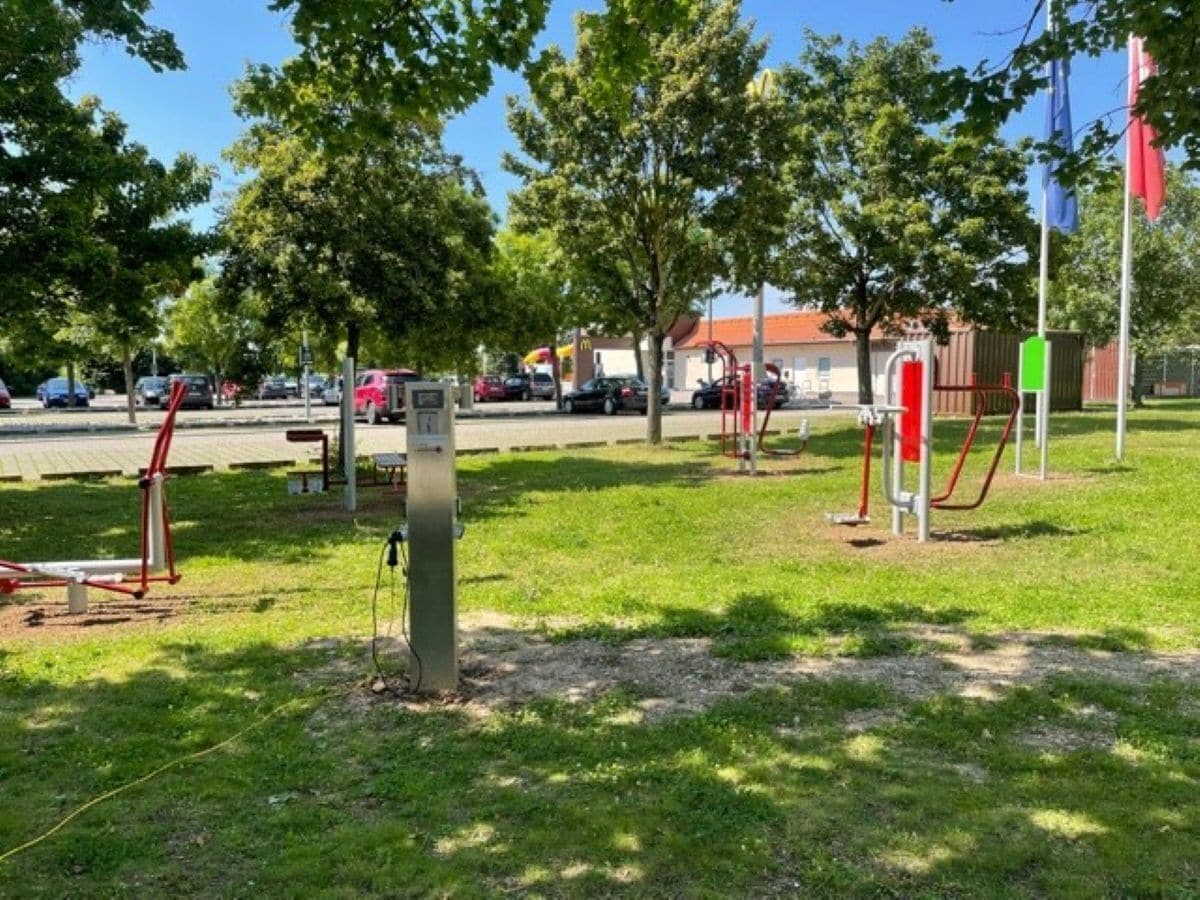 Um parque com equipamentos de ginástica, um parquinho e um restaurante McDonald's ao fundo.