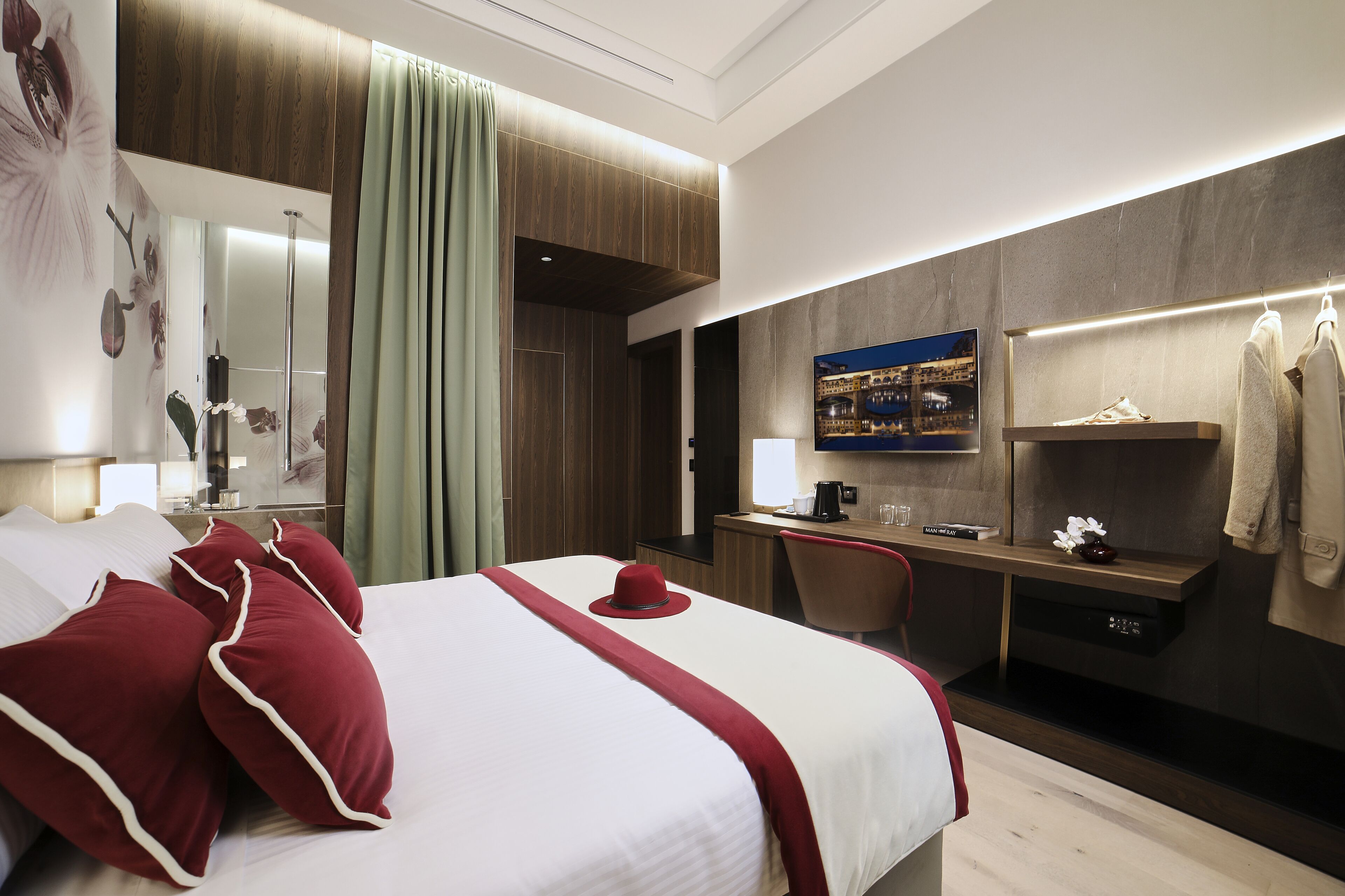 Quarto de hotel com uma cama grande, uma escrivaninha e zona de chuveiro.