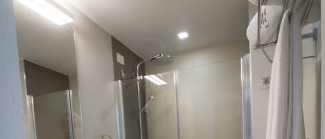 Uma casa de banho moderna com chuveiro em cabine de vidro, lavatório branco e sanita.