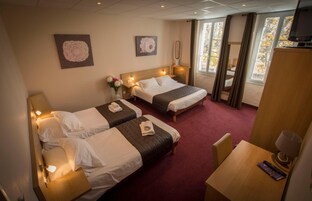 Quarto de hotel com duas camas, uma escrivaninha, uma cadeira e uma televisão.