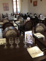 Um restaurante com mesas e cadeiras de madeira escura, cada conjunto com copos de vinho e cardápios.