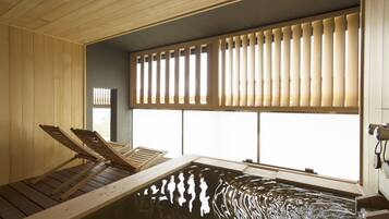 Uma onsen japonesa tradicional com bancos de madeira e uma grande janela com persianas verticais.