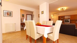 Uma área de refeições com uma mesa posta para quatro pessoas, uma cozinha ao fundo e um radiador na parede.