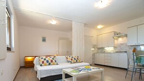 Um espaço compacto com cama, mesa pequena, cozinha compacta e janela.