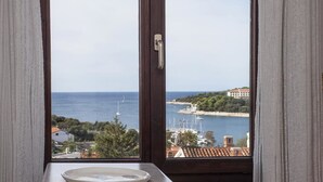 Quarto com vista para o mar, um prato no parapeito da janela e uma porta com puxador.