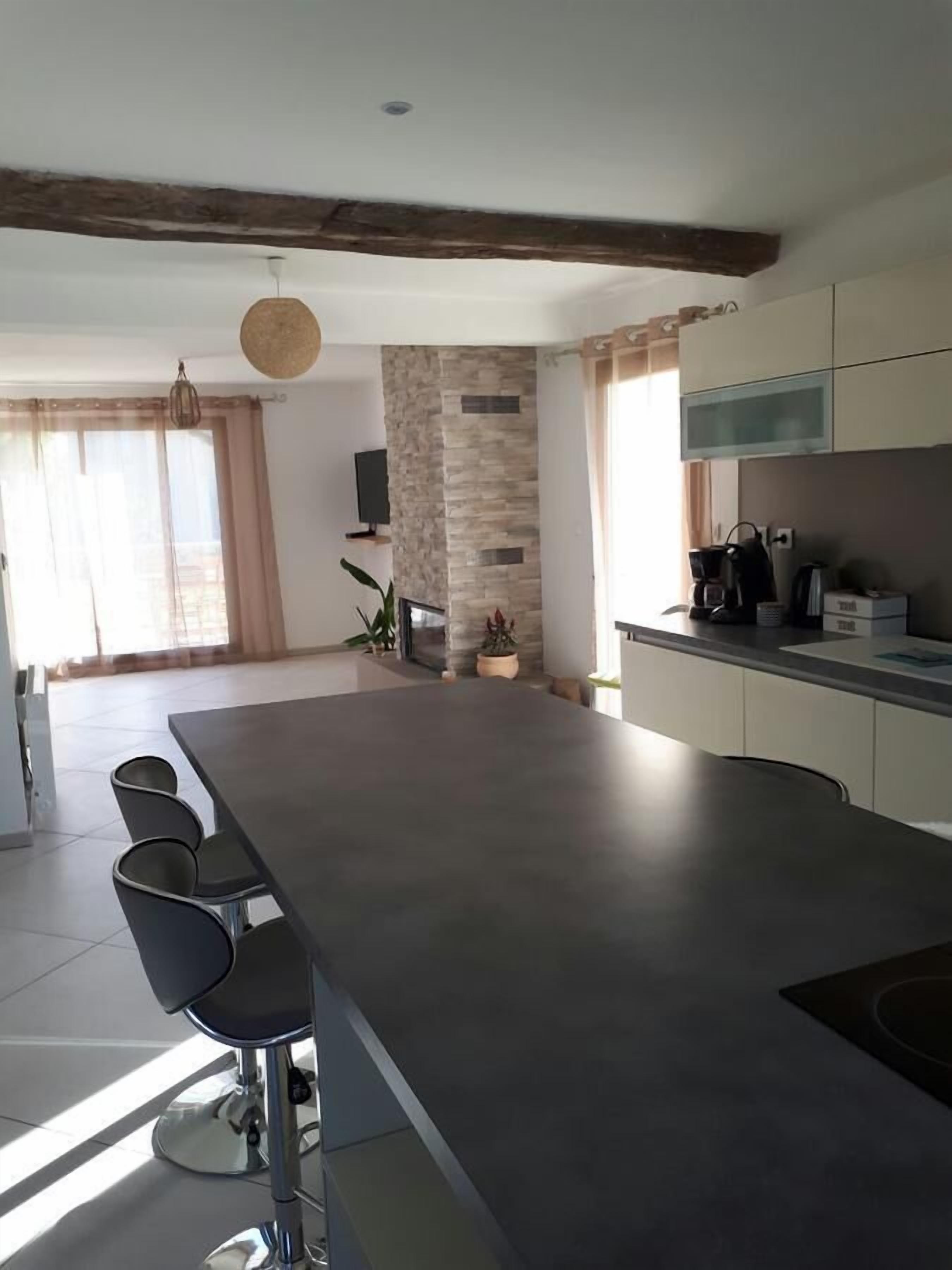 Uma cozinha moderna com uma ilha grande, banquetas e uma parede decorada com pedra.