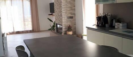 Uma cozinha moderna com uma ilha grande, banquetas e uma parede decorada com pedra.